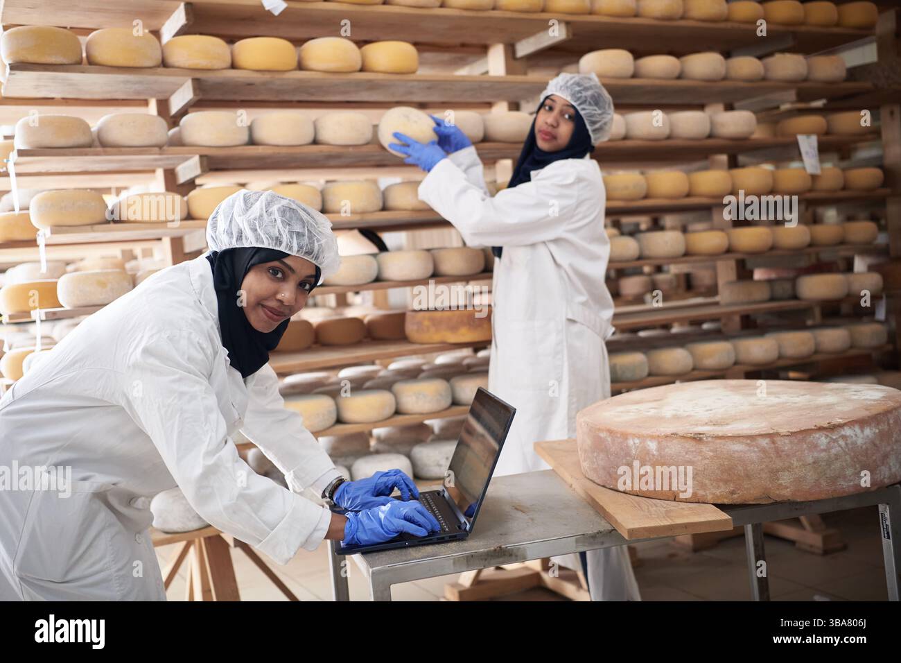 Smiling Middle Eastern female workers in hijab and white uniforms ...