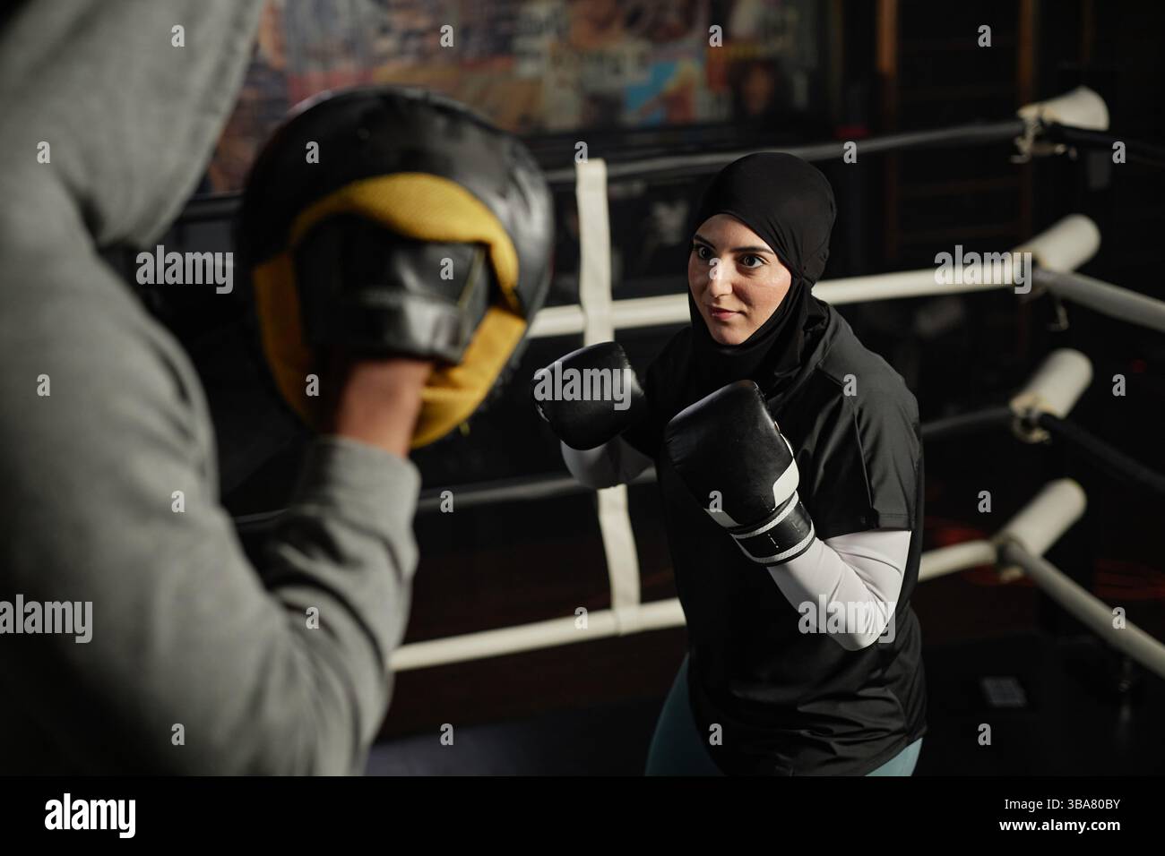 Mixed-race Muslim woman in hijab, activewear and leather boxing gloves ...