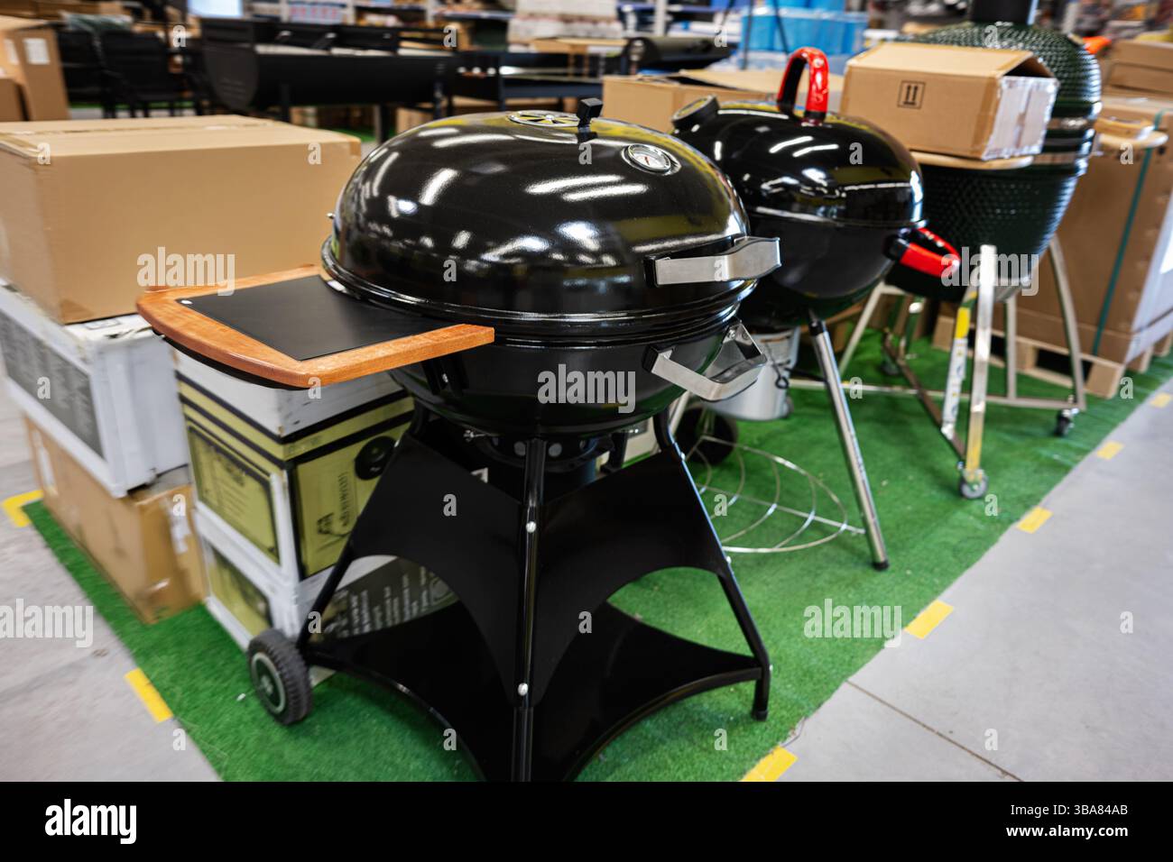 Stylish black barbecue grills with features shown in a warehouse with ...