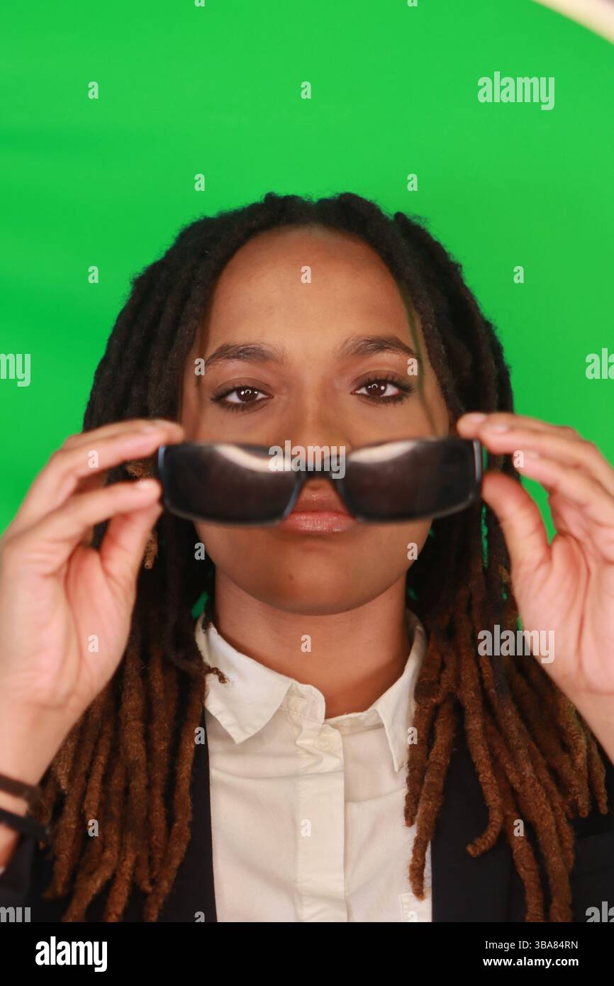 Black woman of Afro-Caribbean descent with dreadlocks dressed in formal business attire putting ...