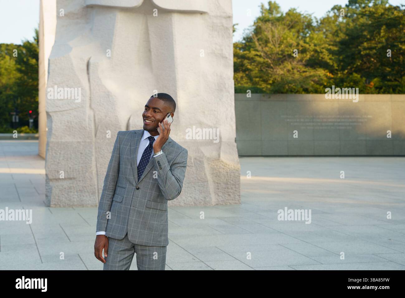 Young black man in business suit talking on cellphone in front of ...