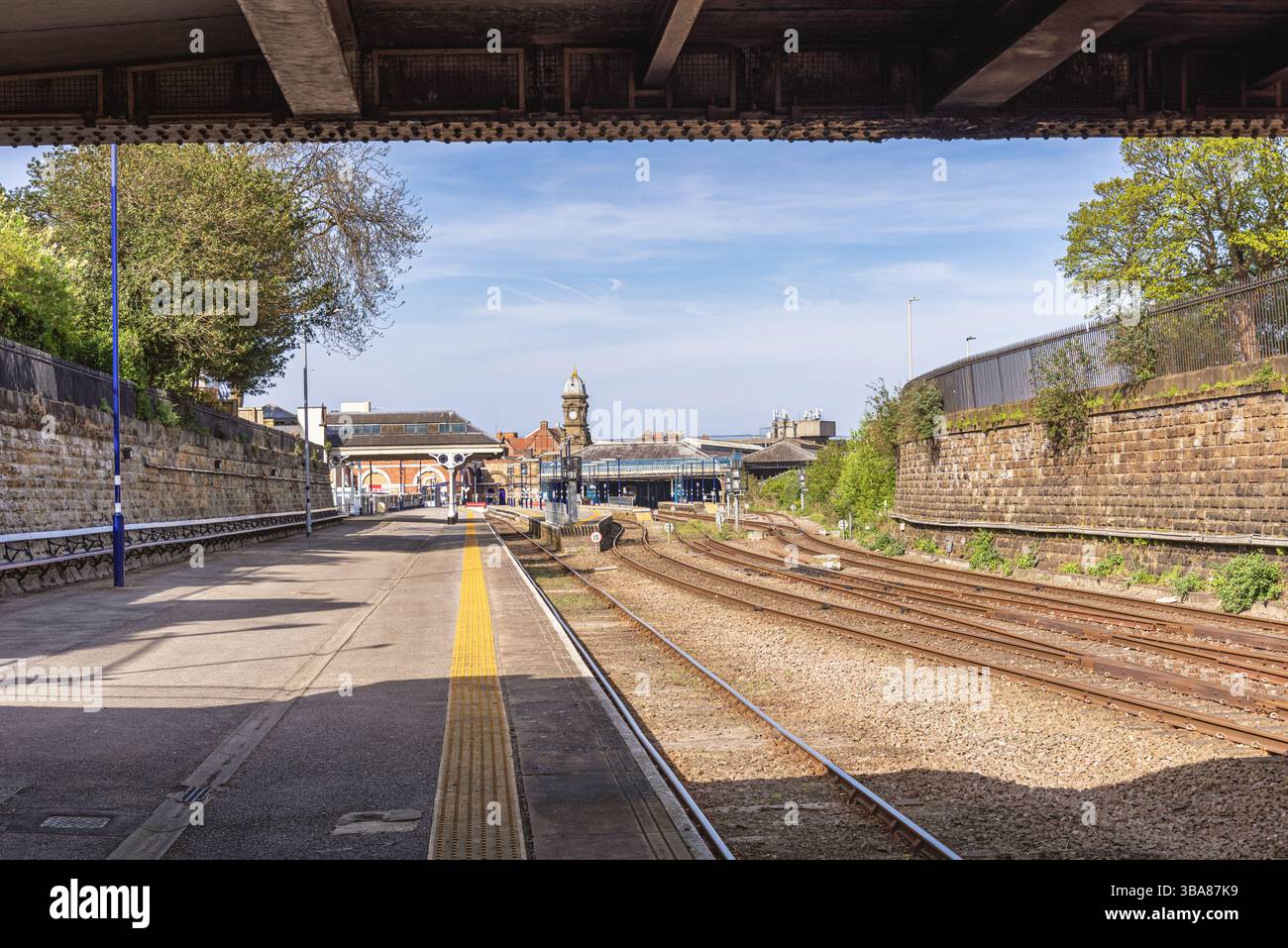 A railway station viewed from under a metal bridge. Rail tracks lead to ...