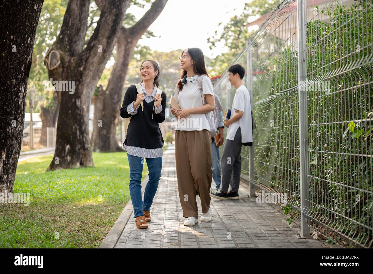 Two young Asian female students best friends are laughing and enjoying ...