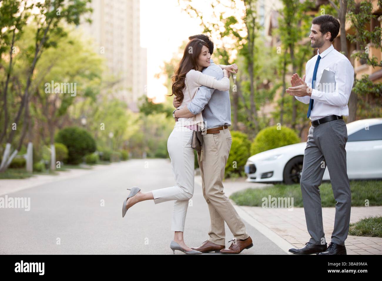 Smiling Chinese couple hugging each other receiving house key from ...