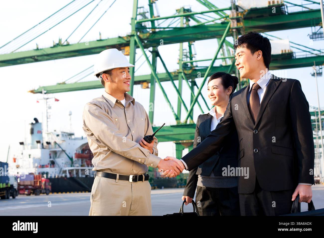 Chinese businesspeople and a shipping industry worker shaking hands at ...