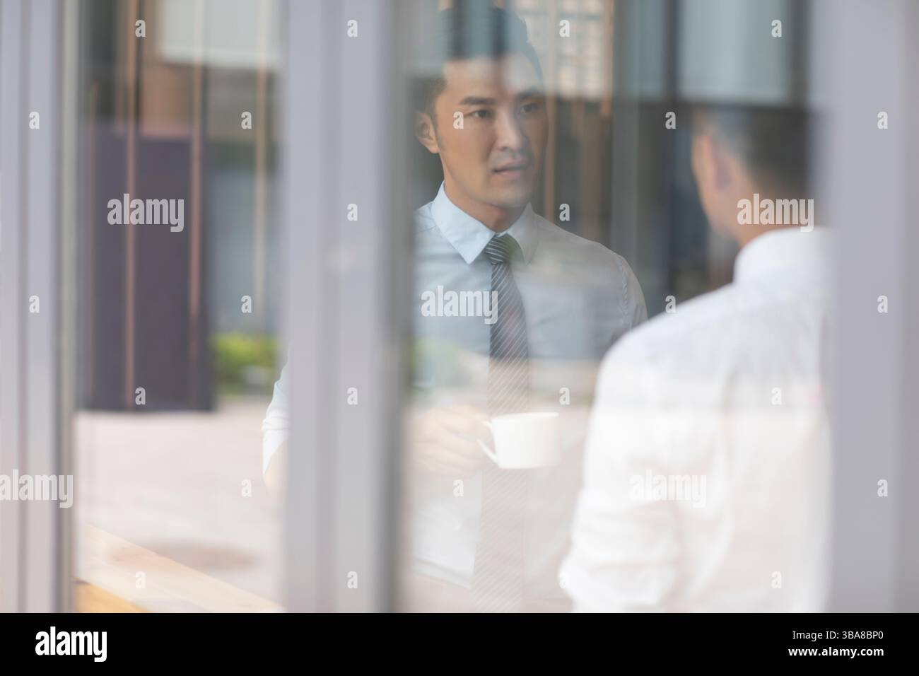 Chinese businessmen talking standing behind glass wall in cafe Stock ...