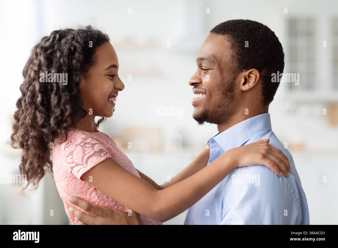 Black father and daughter hugging and looking at each other having fun together at home Stock ...