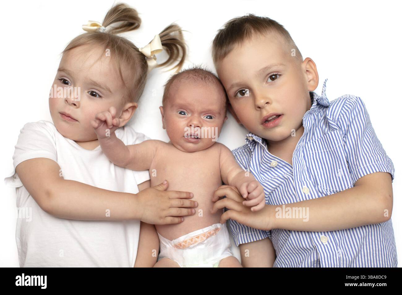 Brother and sister lying together with a newborn baby. Three small ...