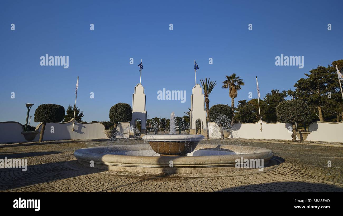 Magnificent fountain on a stone square surrounded by flags and palm ...