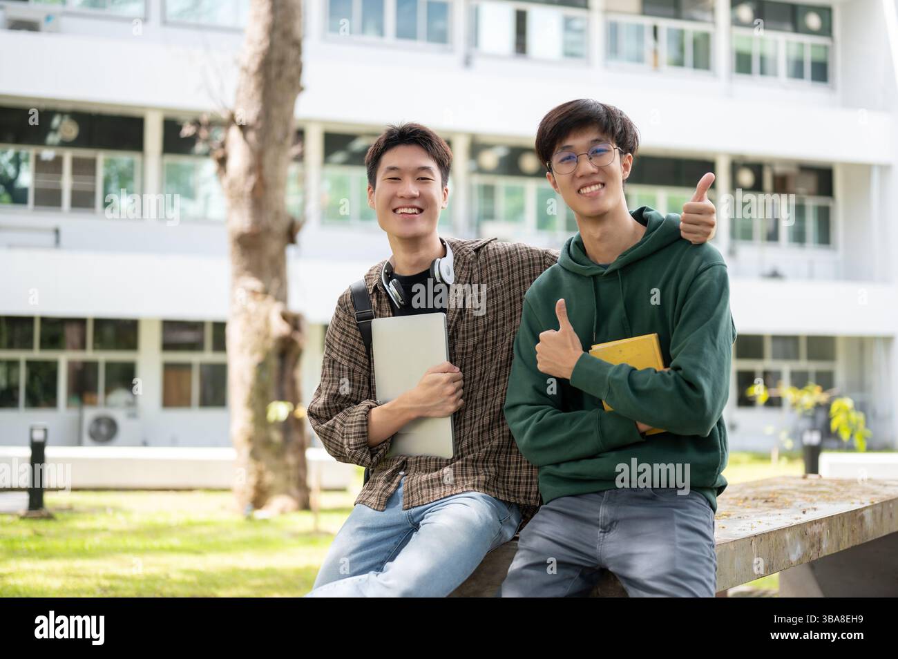 Two cheerful young Asian male university students best friends are ...