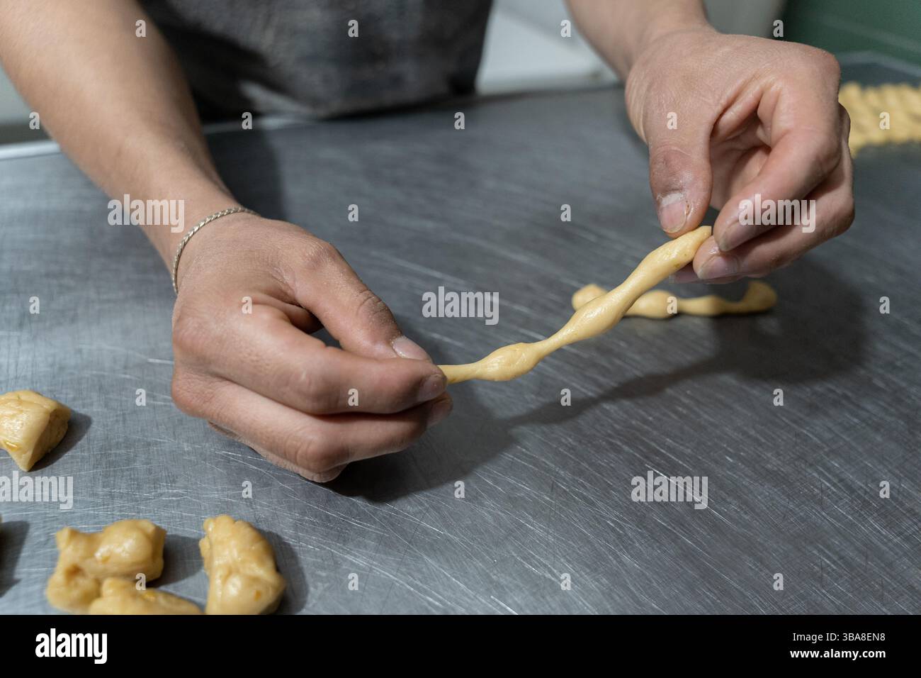 Hispanic baker showing dough bones to prepare day of the dead bread ...