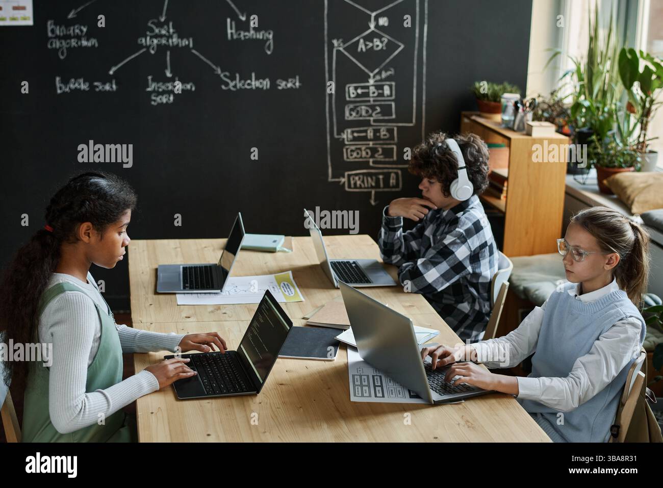 Group of school children working with interface on computers at table ...