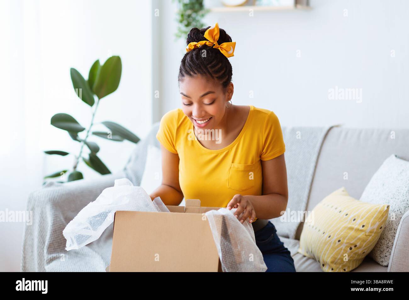 Satisfied Buyer. Portrait of curious cheerful black woman received package, unpacking cardboard ...