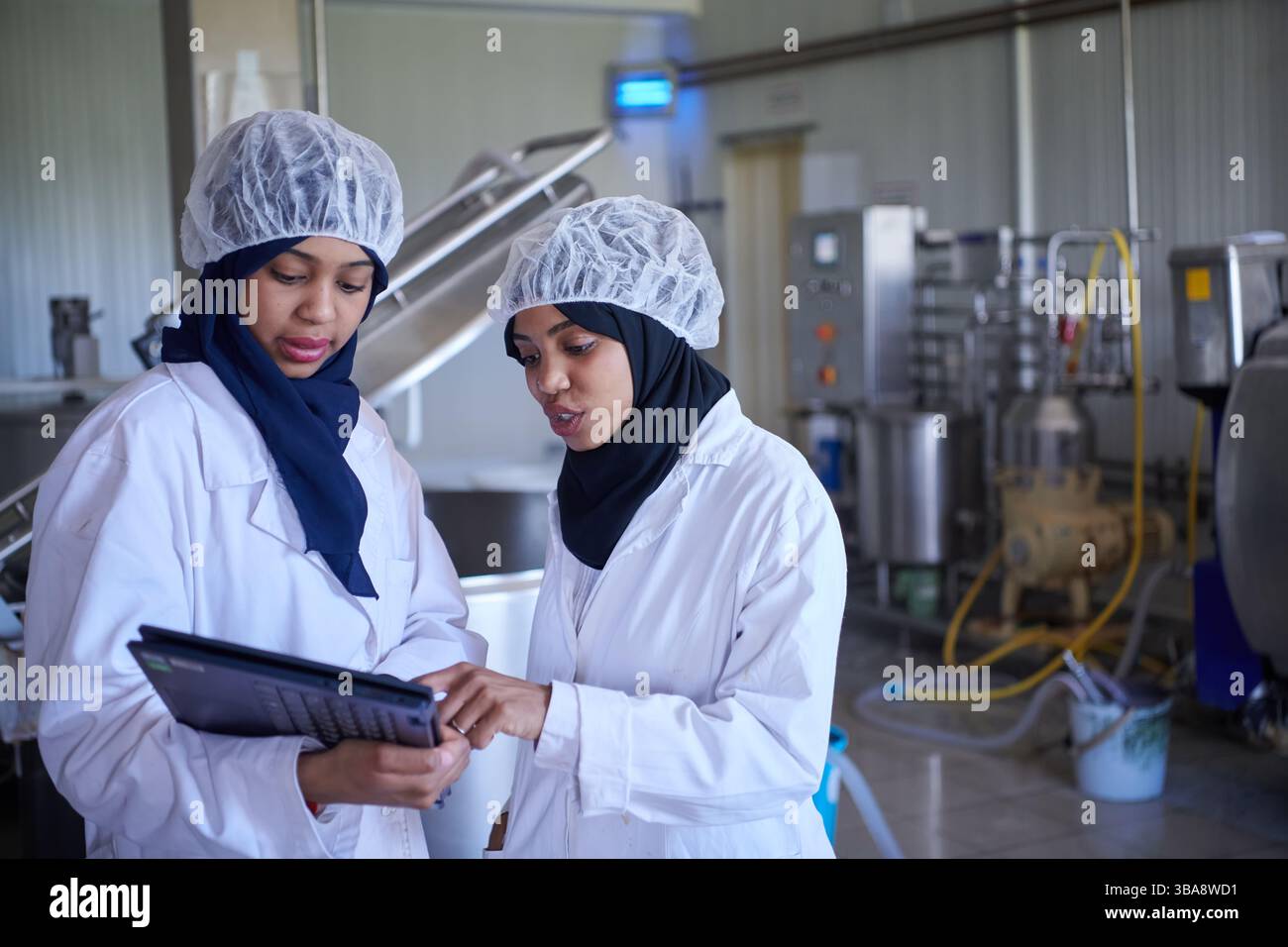 Serious Middle Eastern female factory workers in hijab and white ...