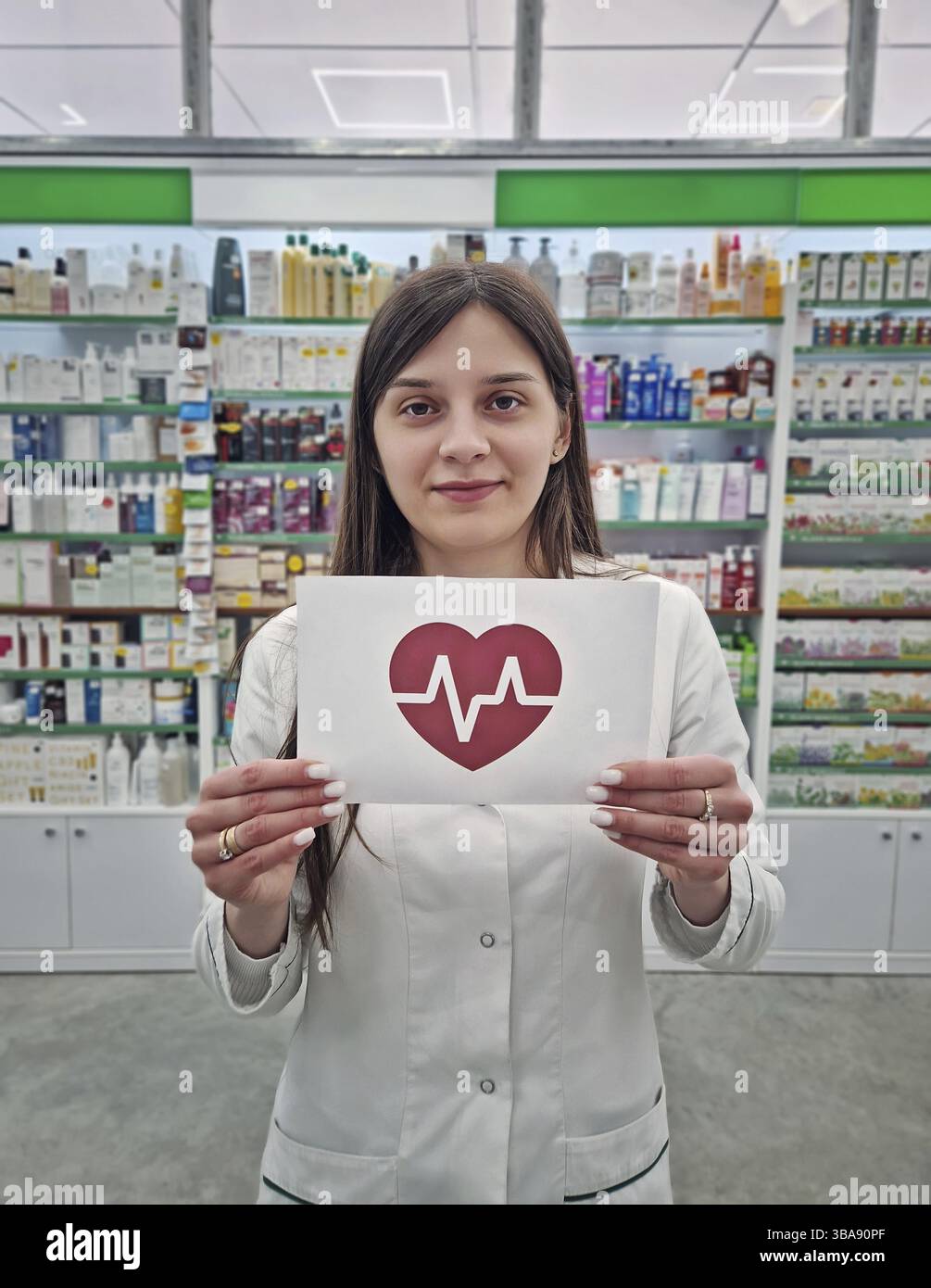 Woman medical worker or pharmacist holding a paper with a heart symbol ...