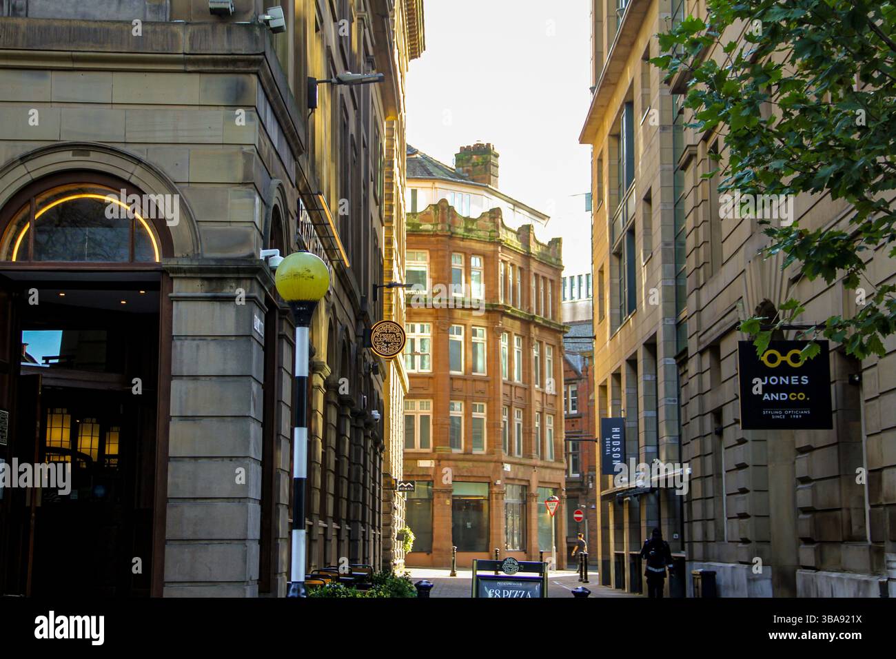 Sunlight casts shadows on tall old buildings in a quiet historic lane ...