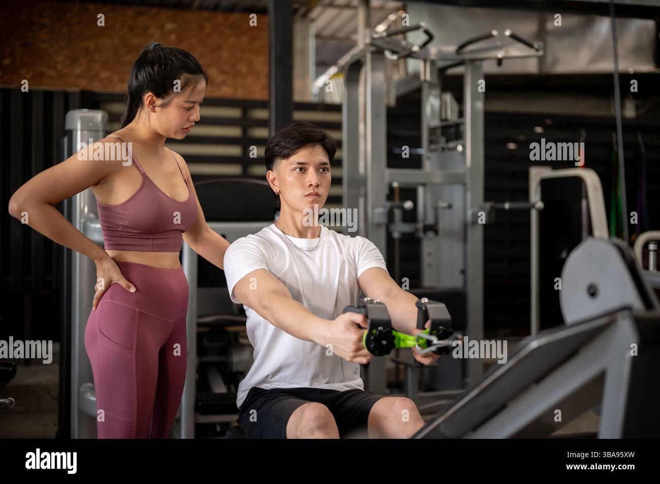 A supportive Asian female fitness trainer is training and instructing a ...