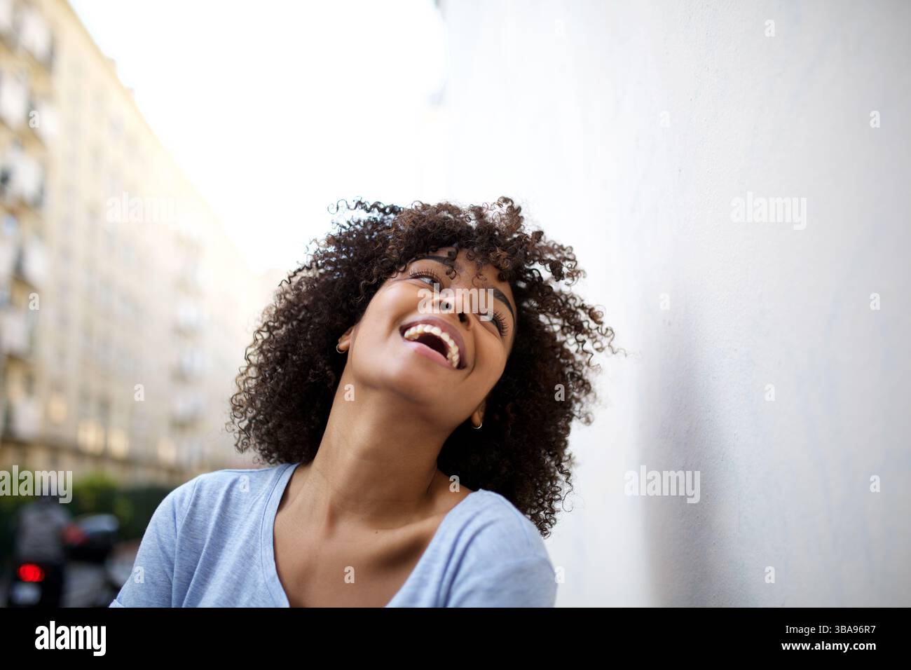 Black female with head tilted backwards standing near white wall on ...