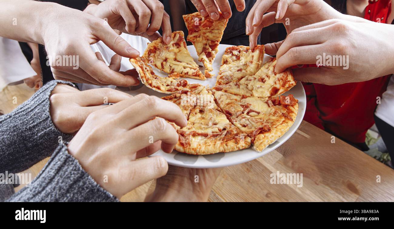 Group of hands grabbing slices of pizza from a plate on the table Stock ...