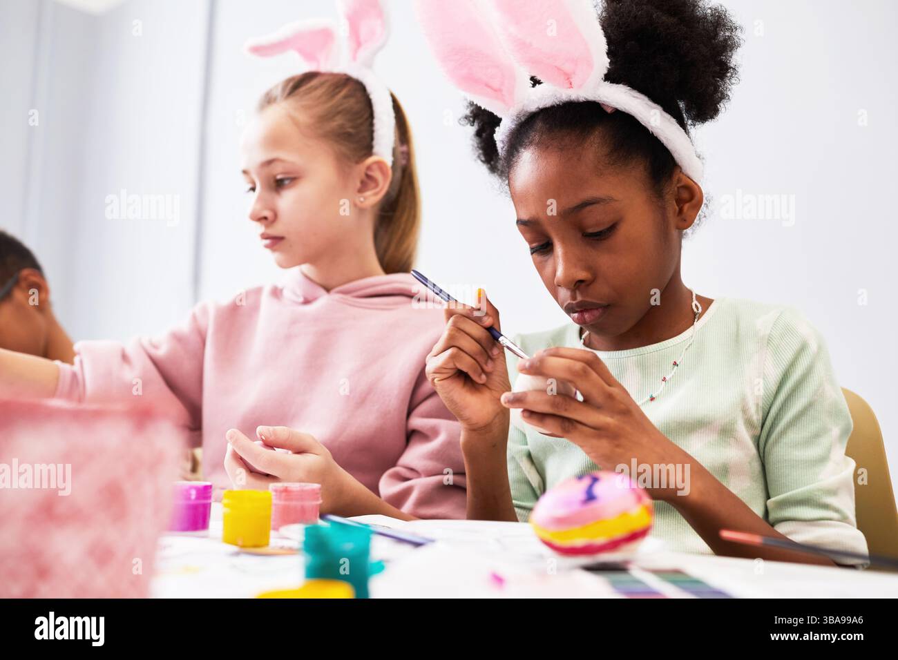 Serious Diverse Group children painting Easter eggs and wearing bunny ...