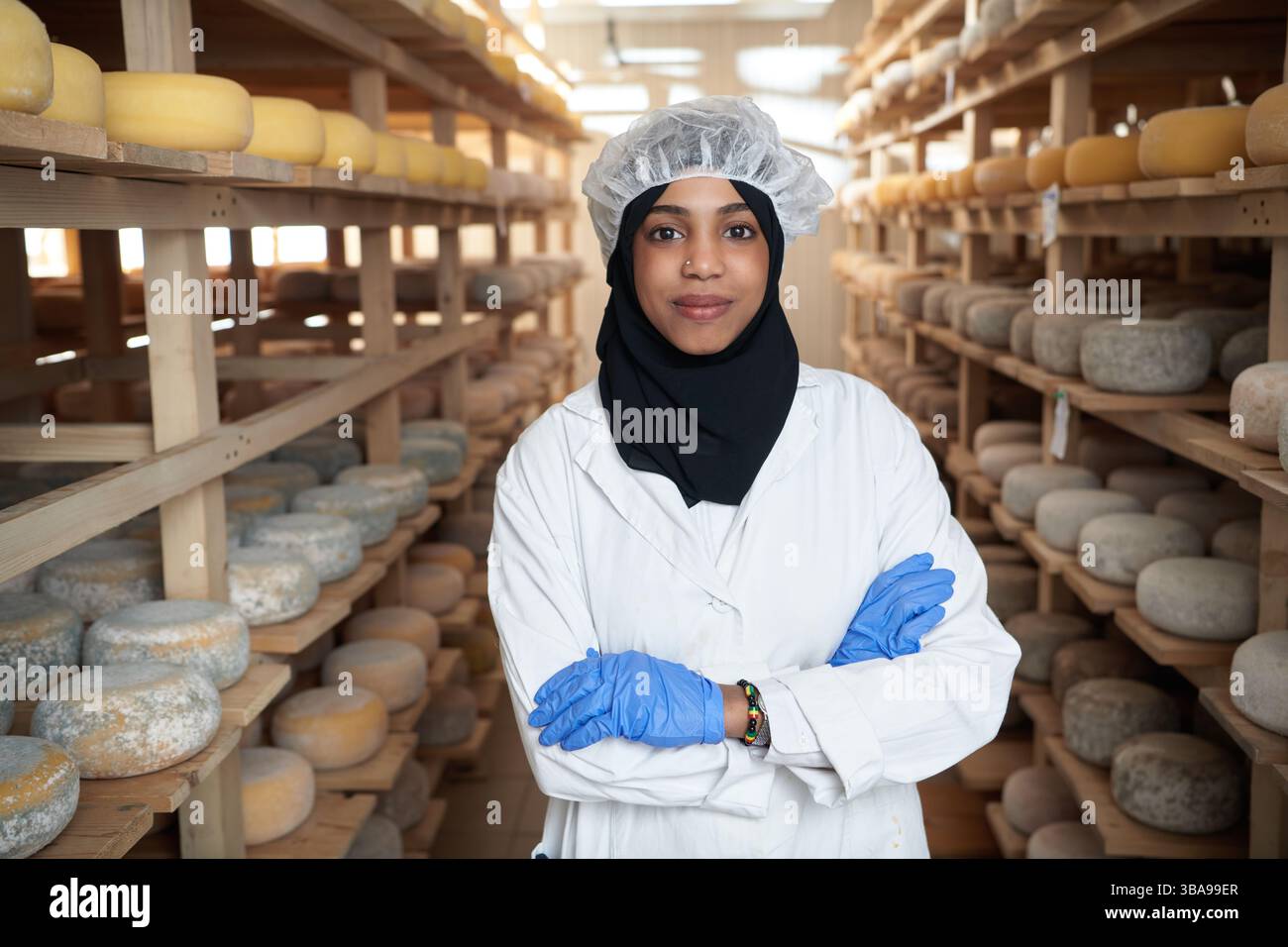 Smiling Middle Eastern female worker in hijab and uniform standing with ...