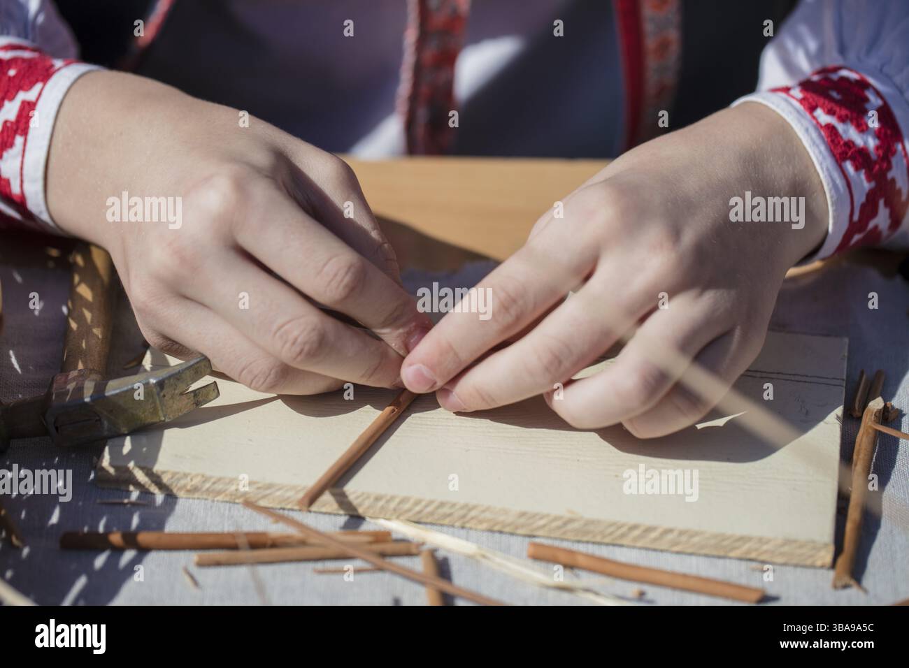 The hands of an artisan create a work of art from straw. Handmade ...