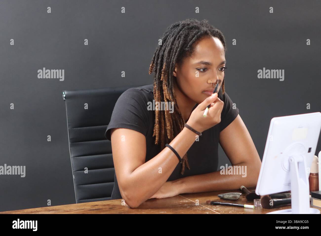 Black woman in her early 20s applying makeup for a beauty tutorial ...