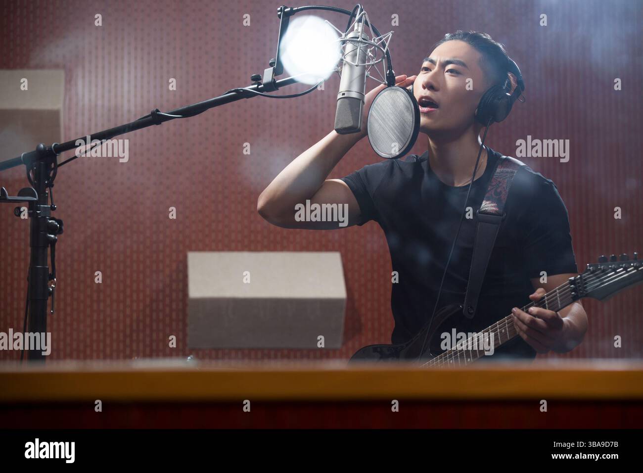 Young Chinese man singing with guitar in recording studio Stock Photo - Alamy
