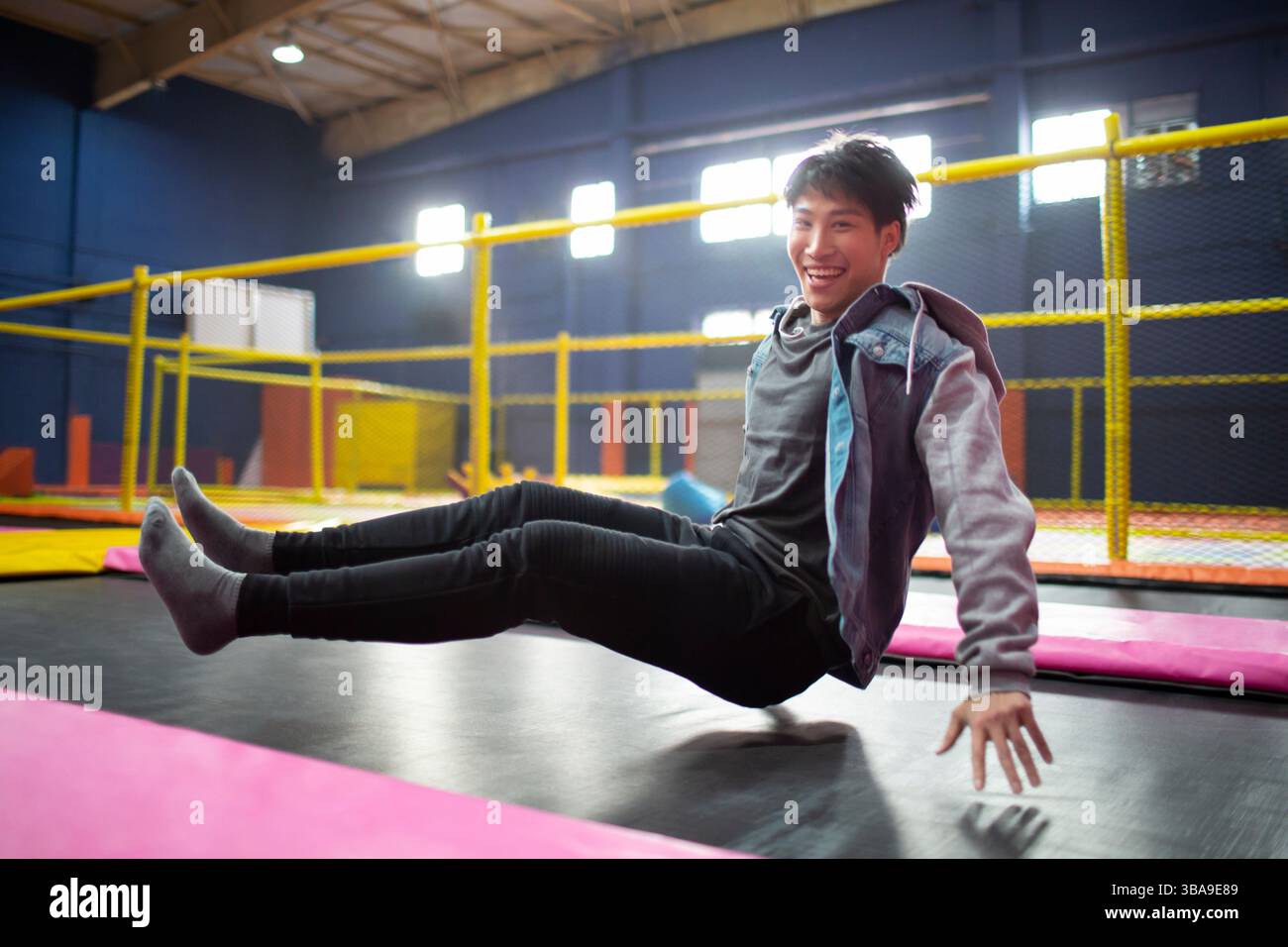 Smiling Chinese man jumping on indoor trampoline park Stock Photo - Alamy