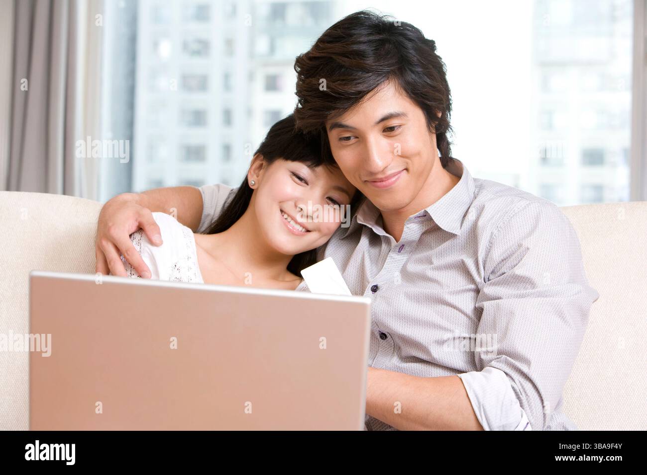 Chinese couple cuddling on a sofa Stock Photo - Alamy