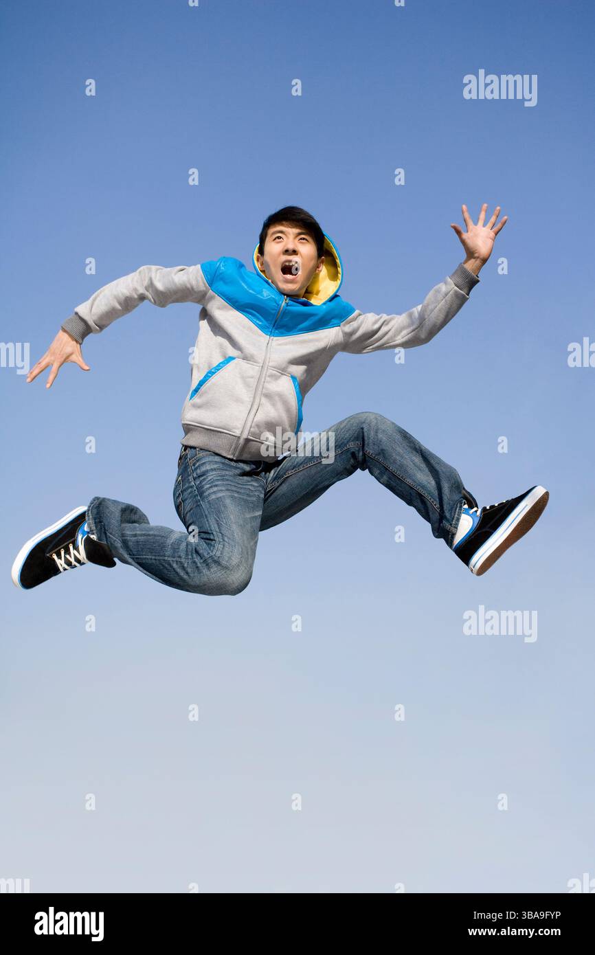 Excited young Chinese man jumping for Joy Stock Photo - Alamy