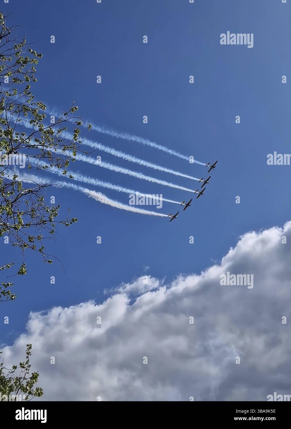 Air show with five airplanes flying in formation with white smoke ...