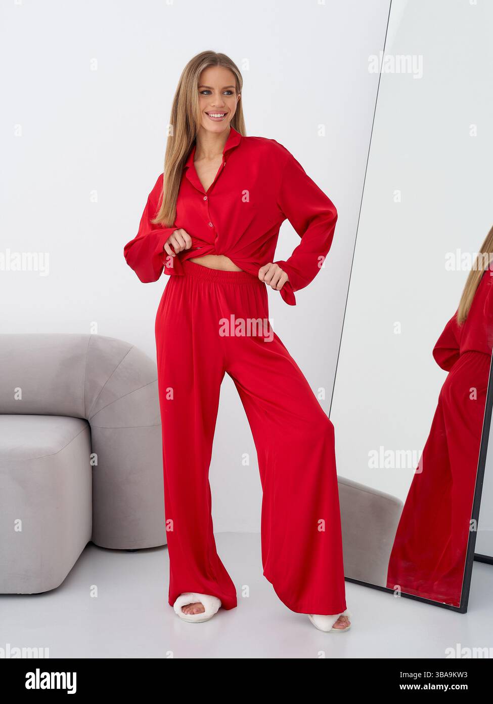 Stylish female model showcases vibrant red outfit in modern studio ...