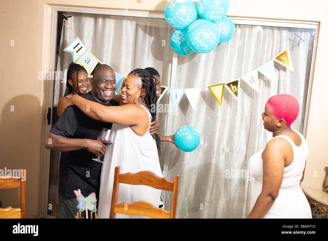 Happy Black parents hugging each other while standing with their ...