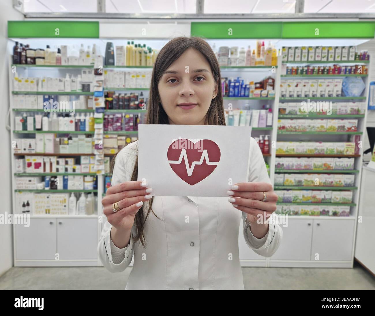 Woman medical worker or pharmacist holding a paper with a heart symbol ...