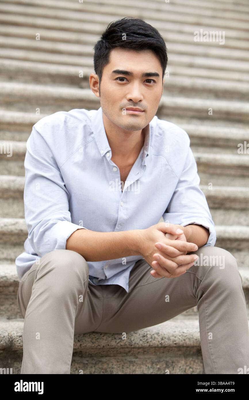 Portrait of young Chinese man sitting on steps in Hong Kong Stock Photo ...