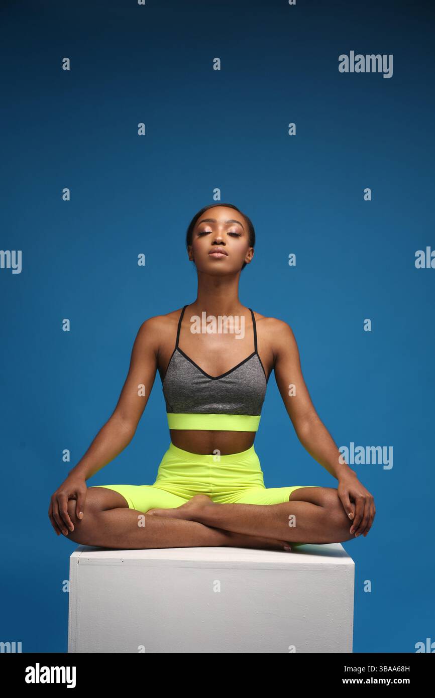 African American woman sitting hands on knees legs crossed eyes closed ...
