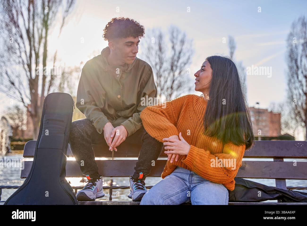 Two happy friends are talking and laughing while sitting on an outdoor ...