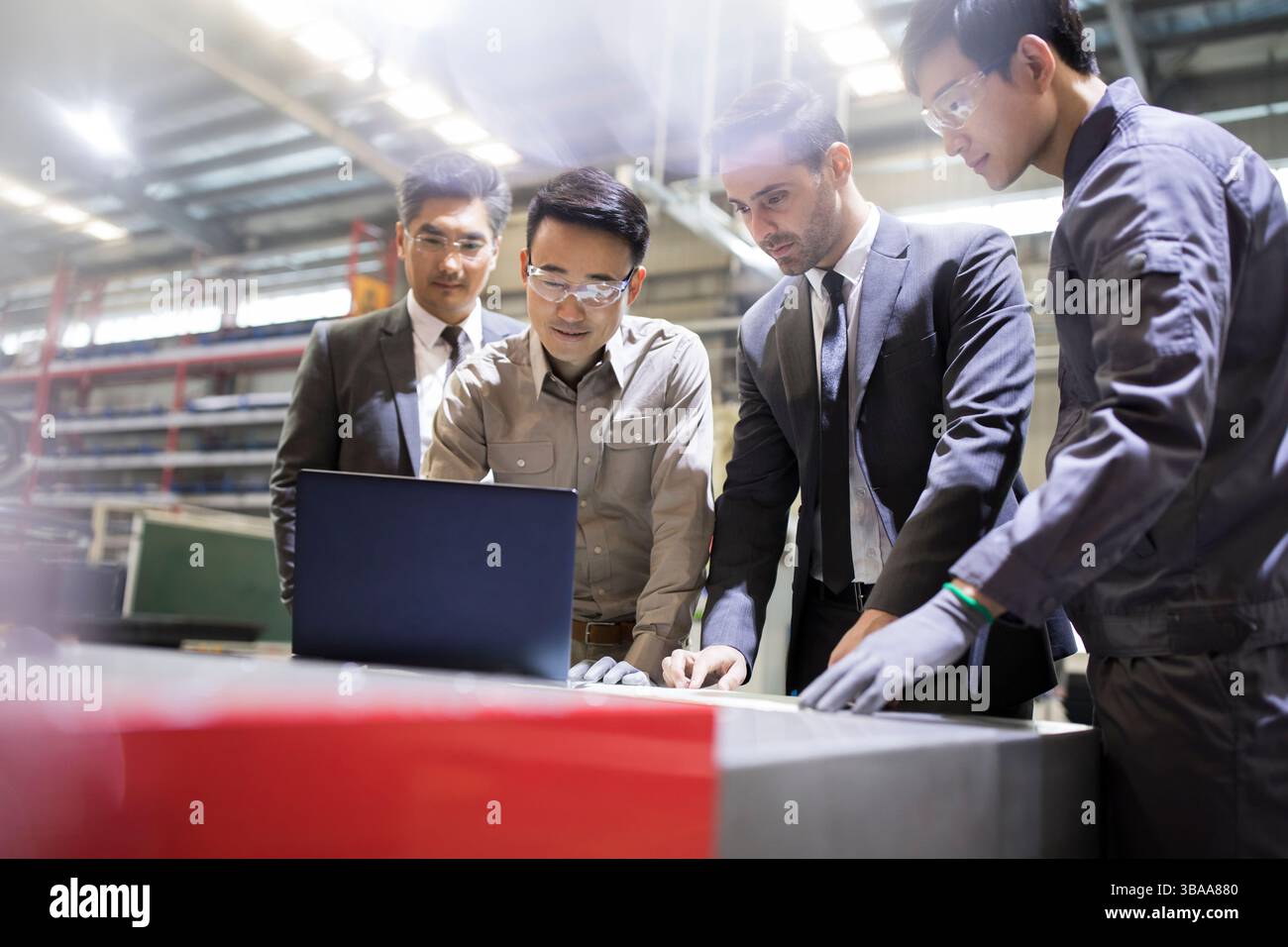 Chinese businessmen and male mechanical engineers looking at laptop ...