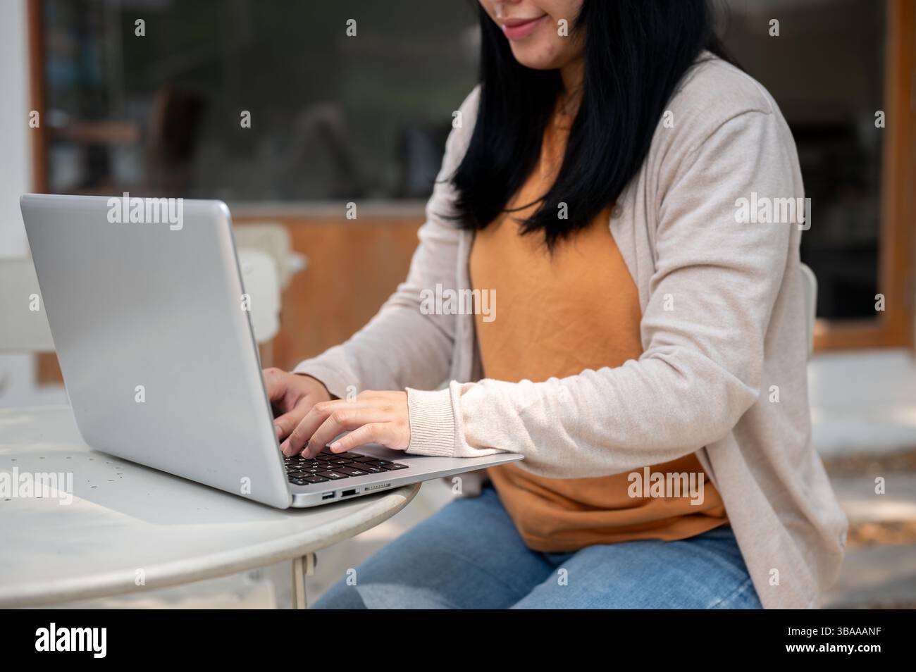 A cropped image of a woman in comfy clothes responds to emails, types ...