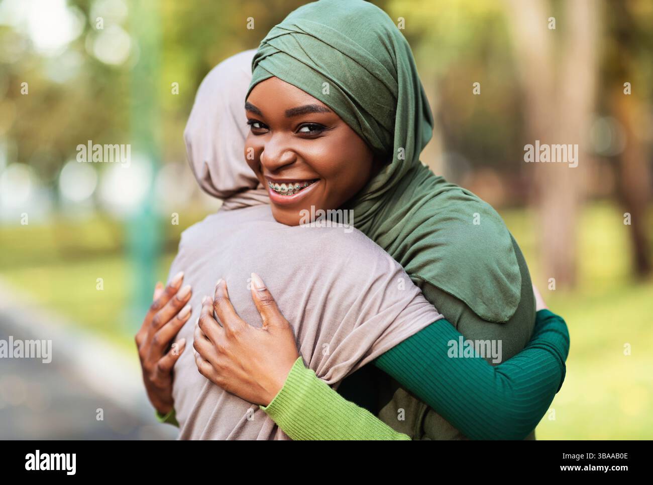 Two Muslim Females Friends Hugging Smiling To Camera Standing In Park ...