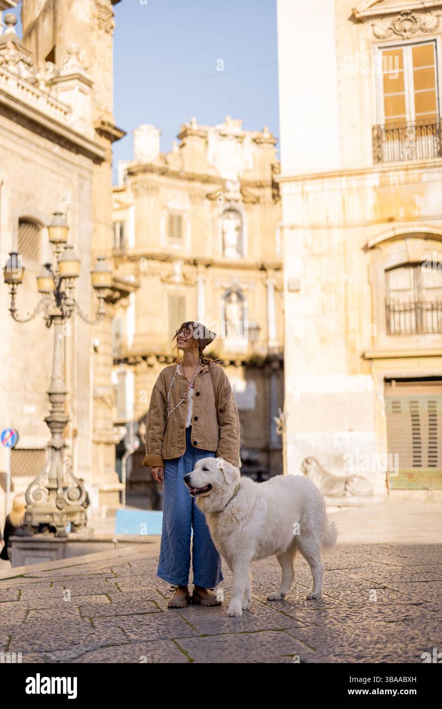 A woman and her white dog enjoy a peaceful morning walk in a historic ...