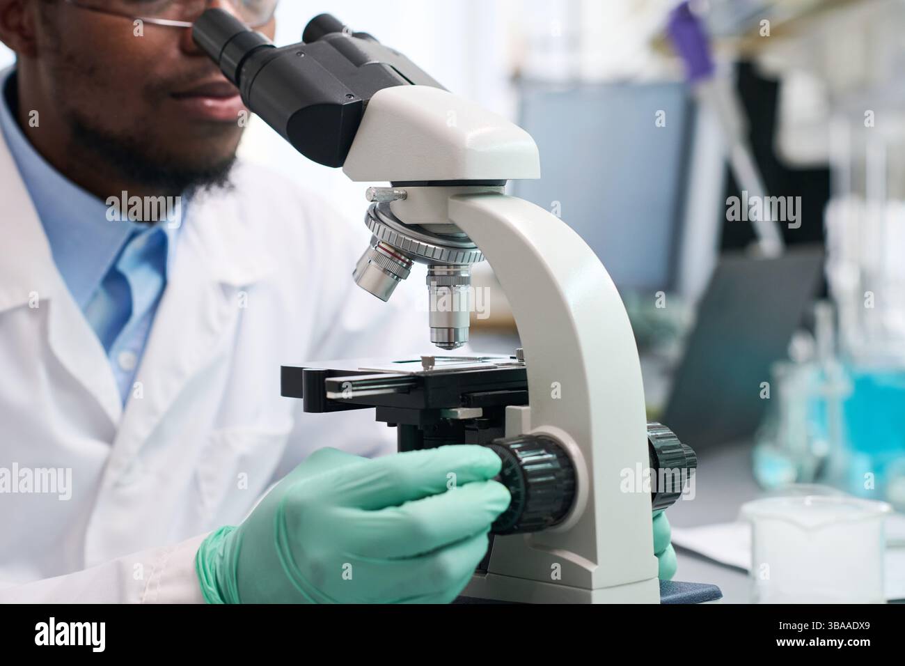 Black male scientist in safety goggles and gloves studying samples with ...