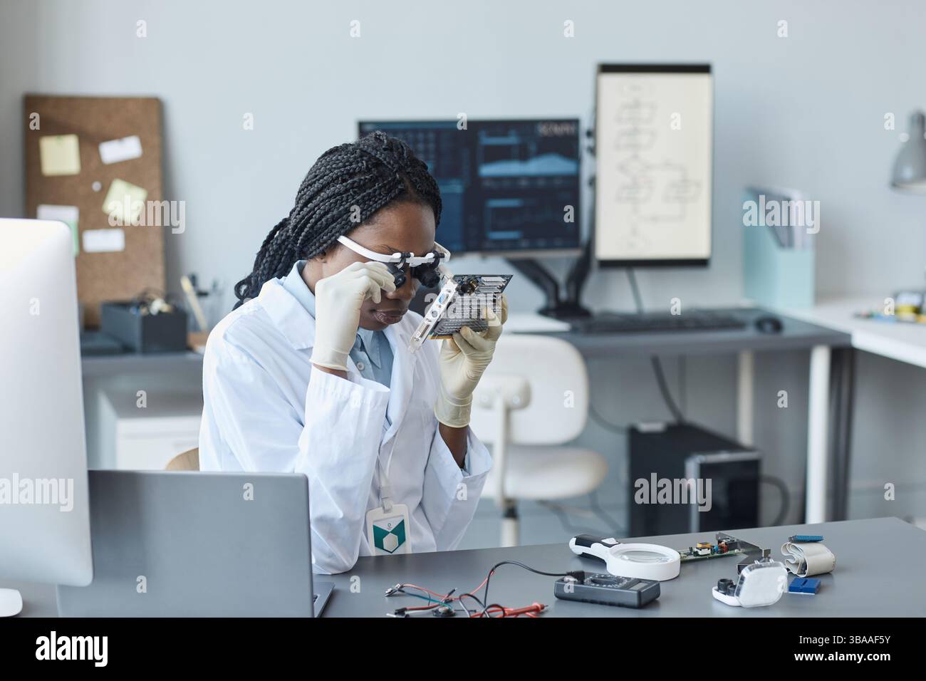 Portrait of young black woman wearing magnifying visor and inspecting ...