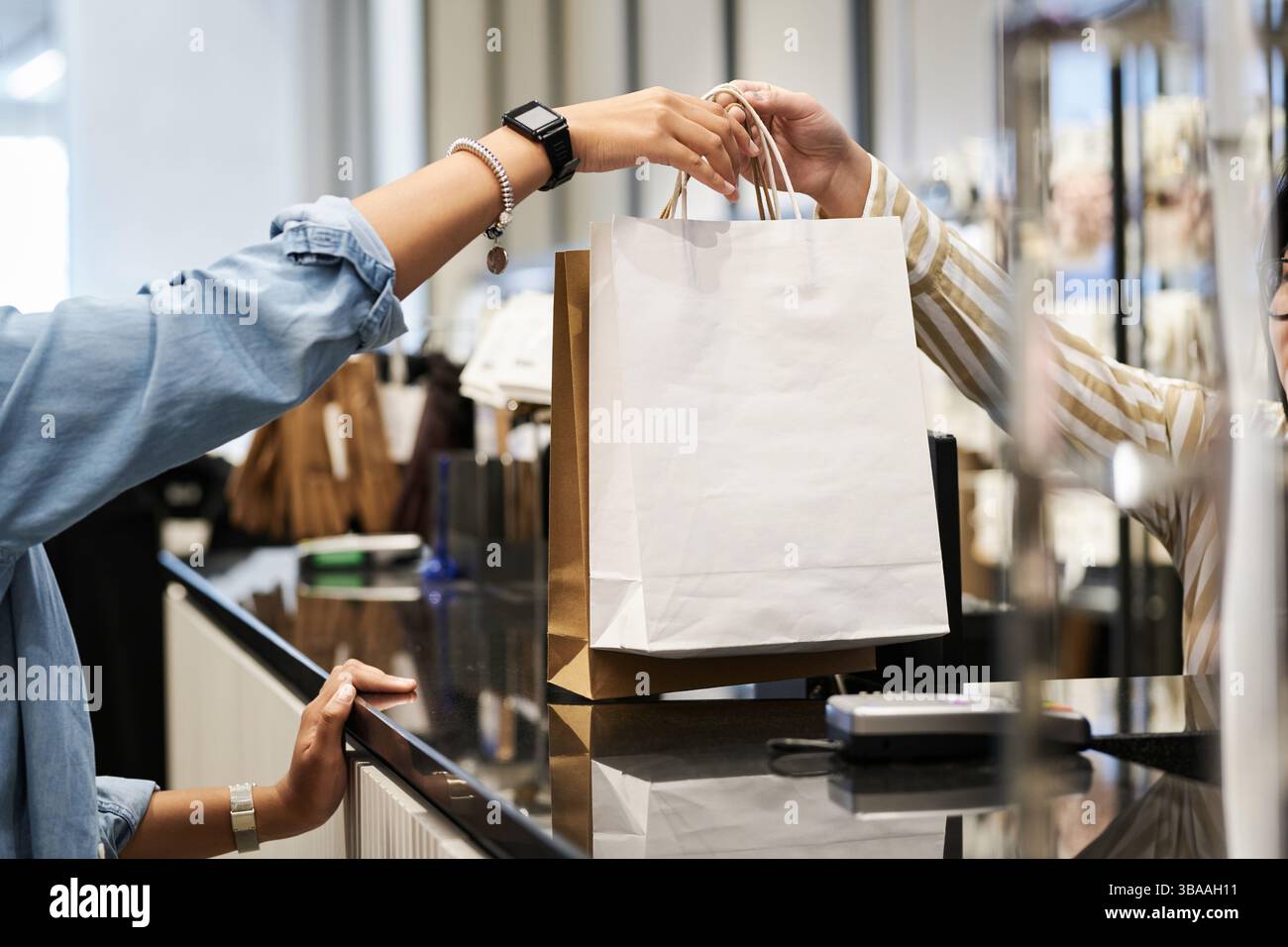 Unrecognizable cashier giving paper bags with purchases to unknown ...