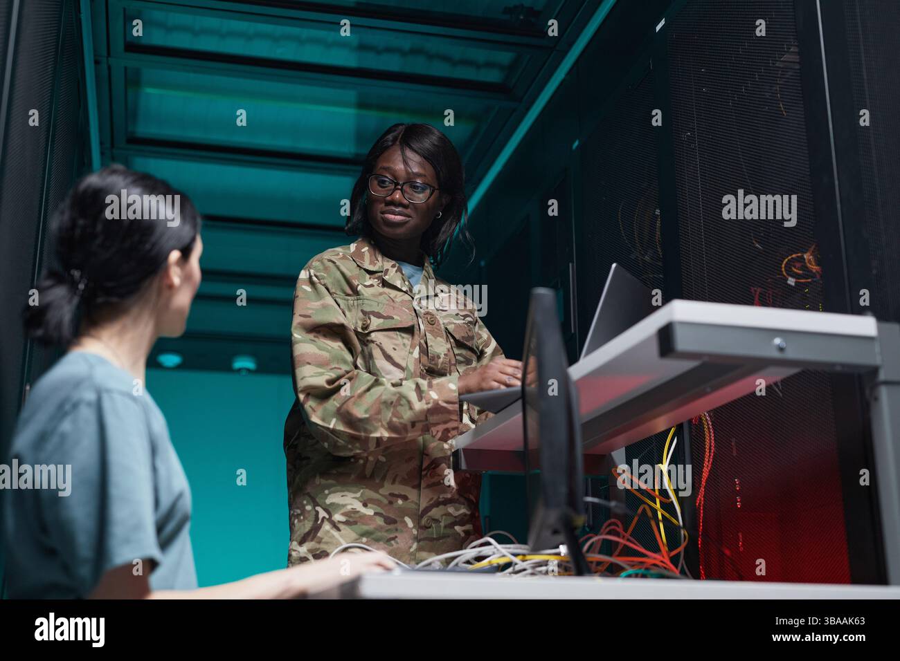 Low angle portrait of young African-American woman wearing military uniform using computer while ...