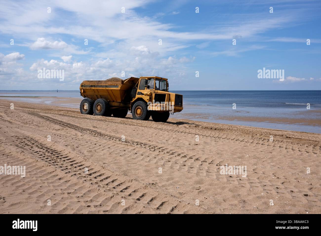 Municipal workers using heavy mechanical tractors redistributing sand ...