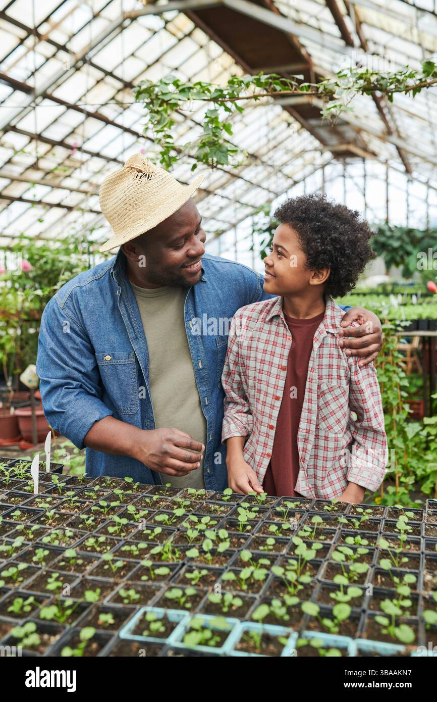 Black father wearing native hat and denim jacket embracing his son ...