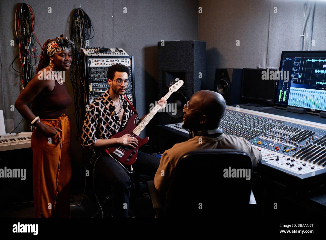 Black music producer and two young musicians discussing something in ...