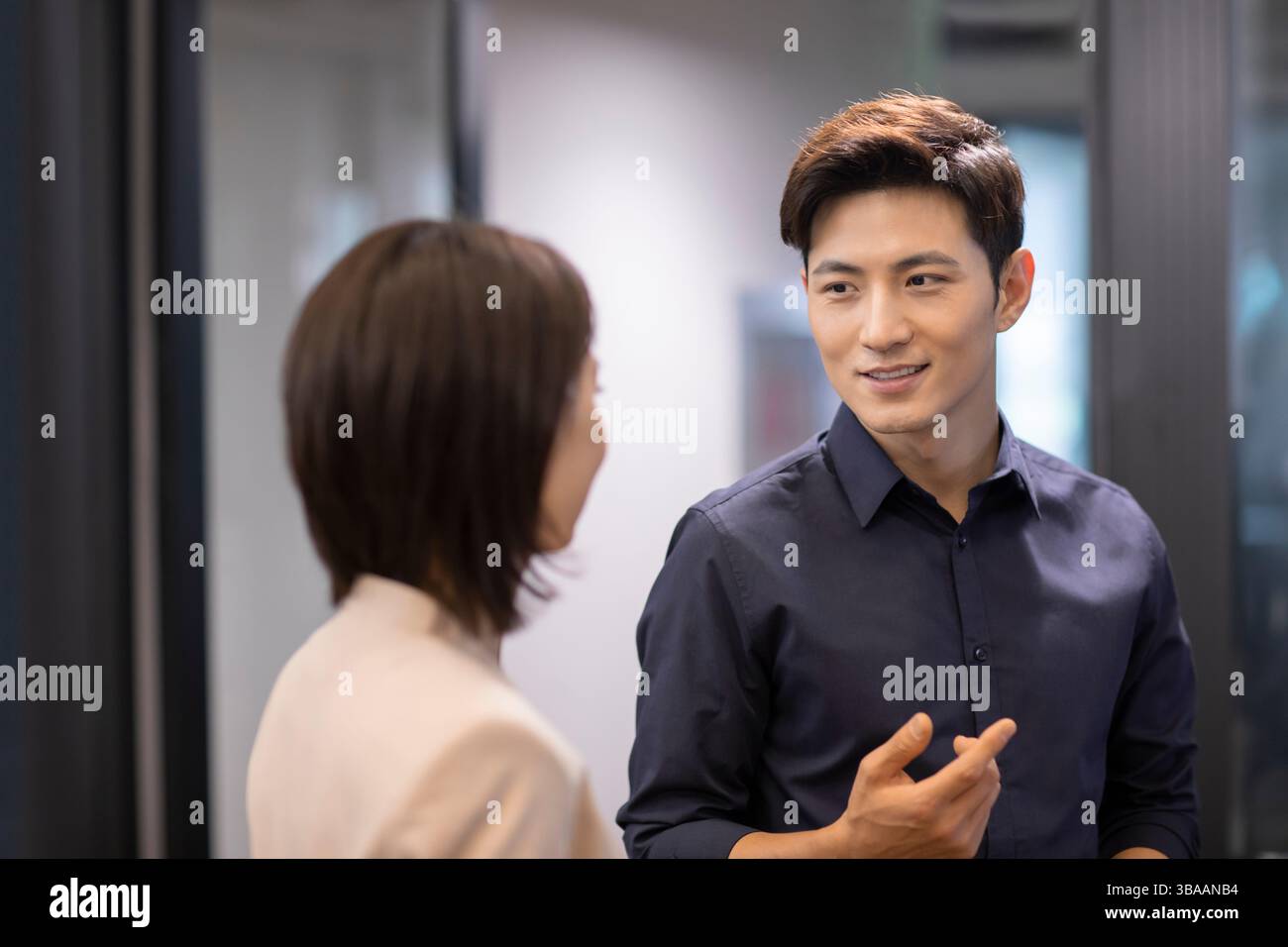 Chinese businessman talking to female colleague standing in office ...